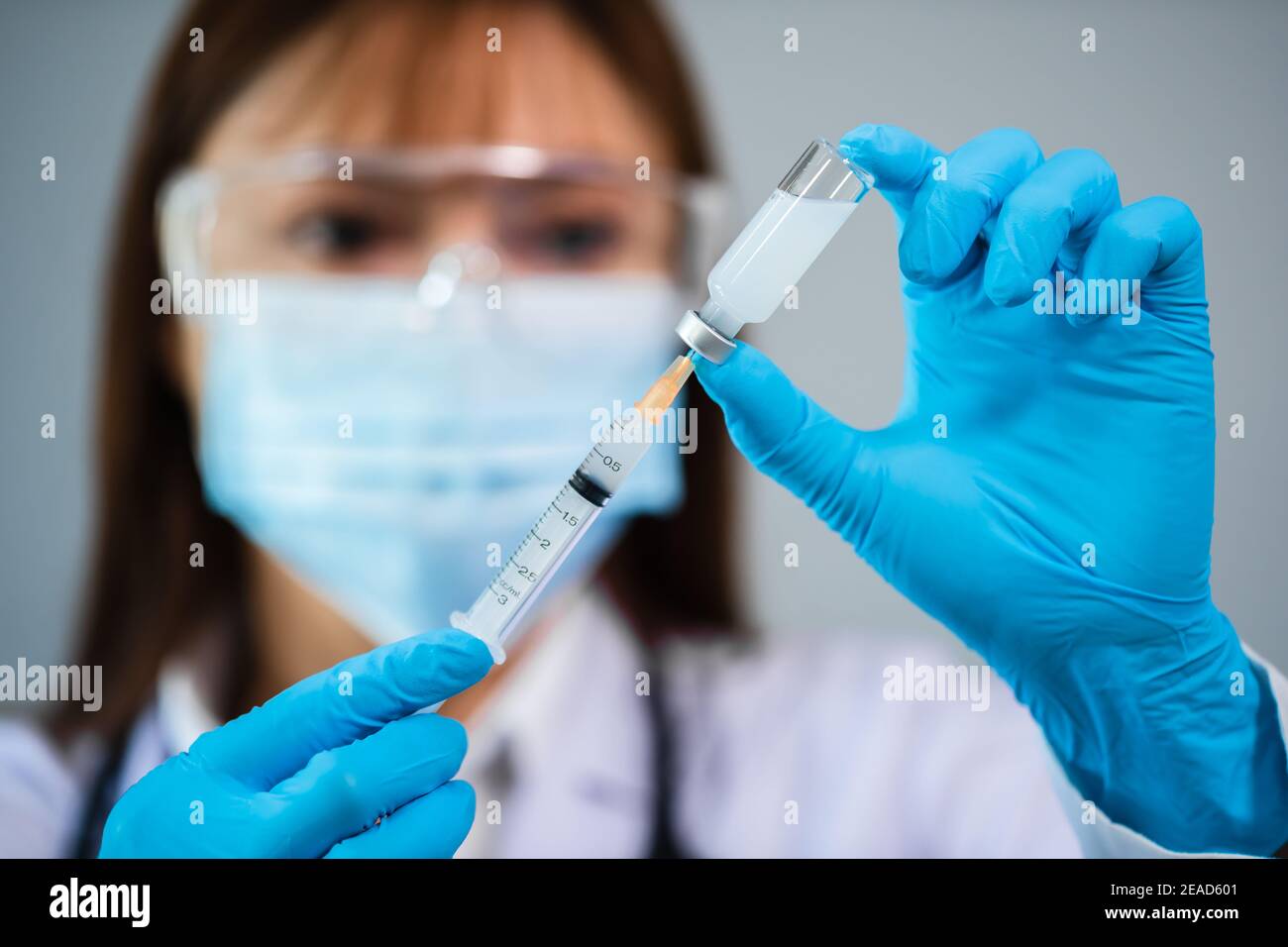 female doctor drawing vaccine bottle into syringe injection medicine ...