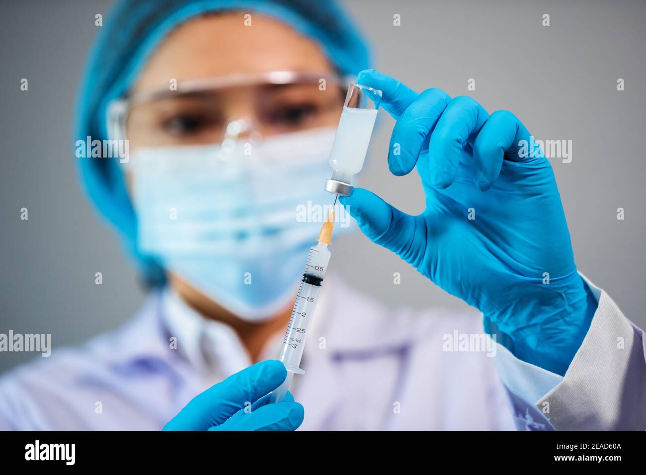 female doctor drawing vaccine bottle into syringe injection medicine ...