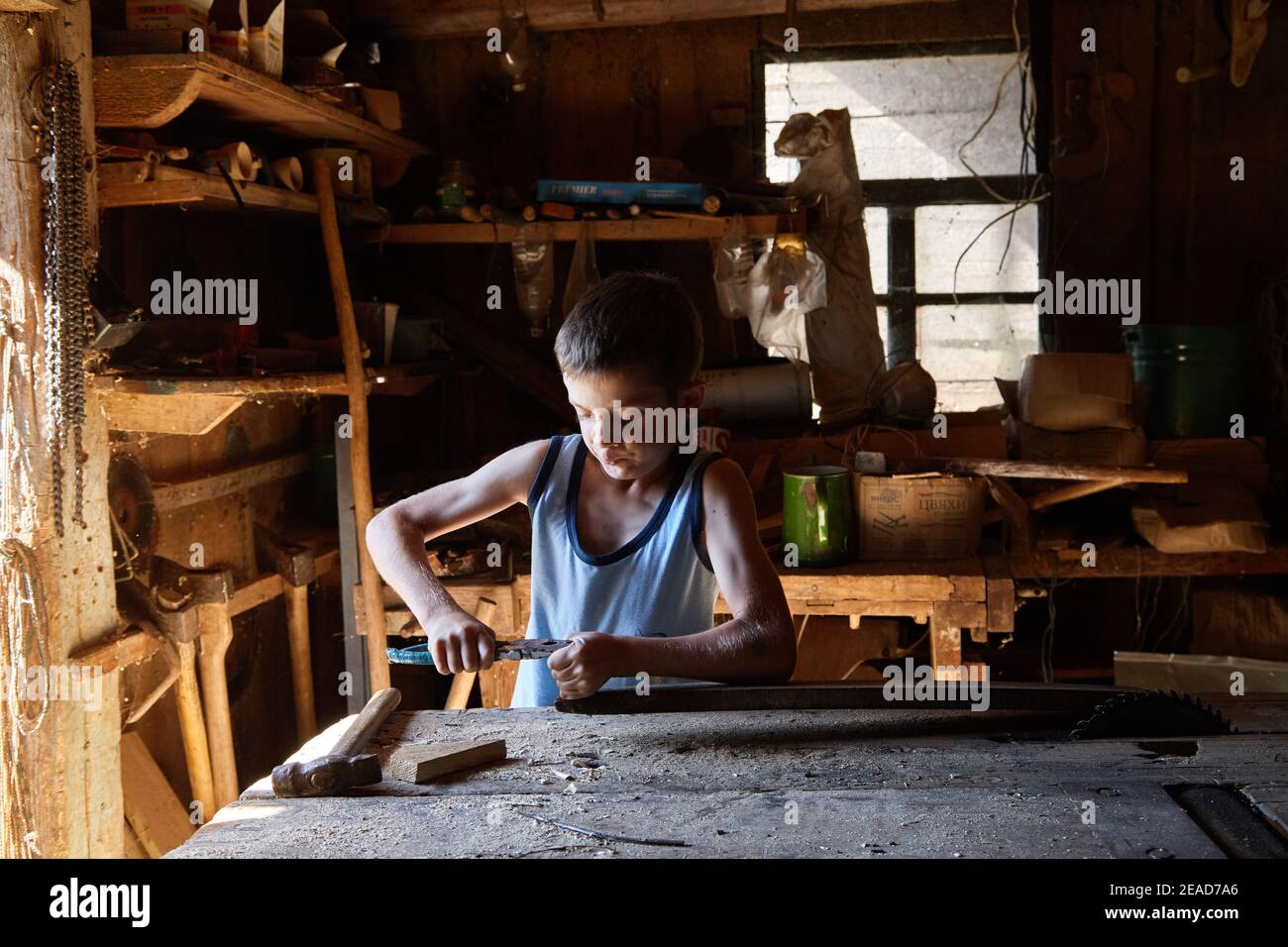 Young hard working boy is making a wooden toy inside the workshop lab ...