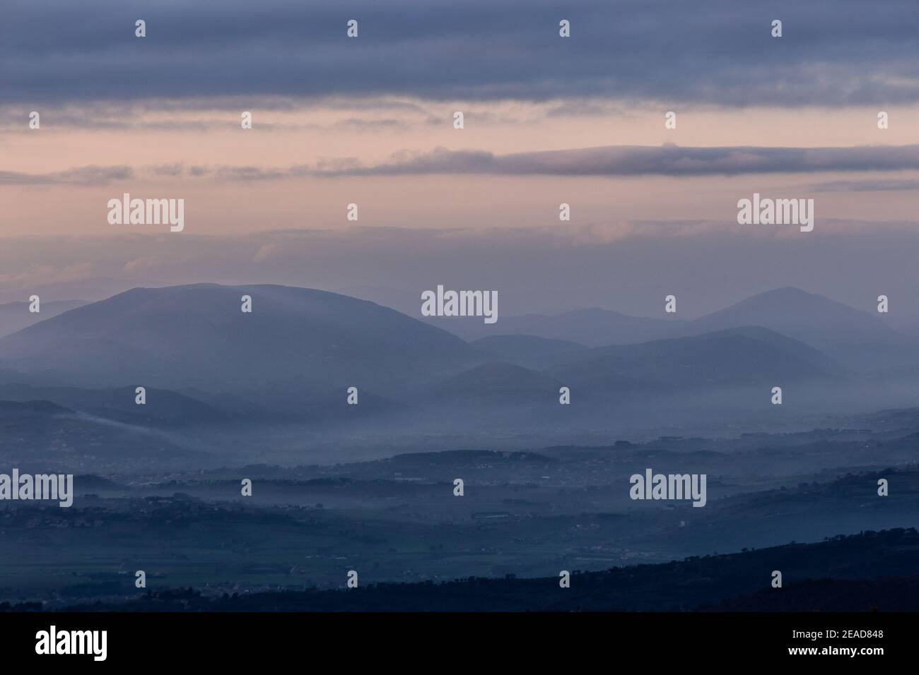 Mist and fog between valley and layers of mountains and hills at dusk ...