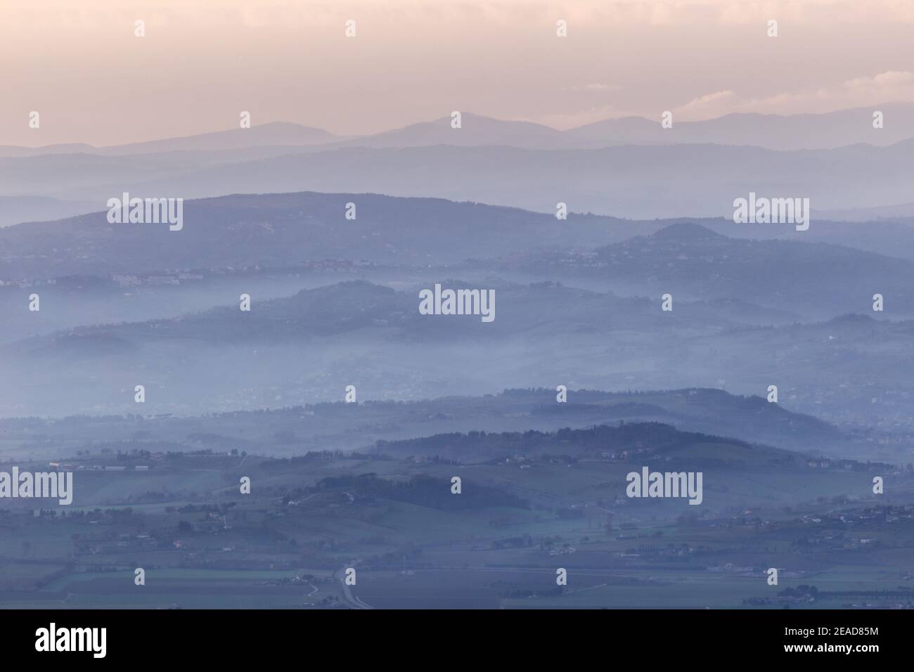 Mist and fog between valley and layers of mountains and hills at dusk ...