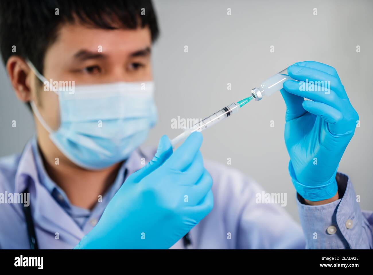 male doctor drawing vaccine bottle into syringe injection medicine ...