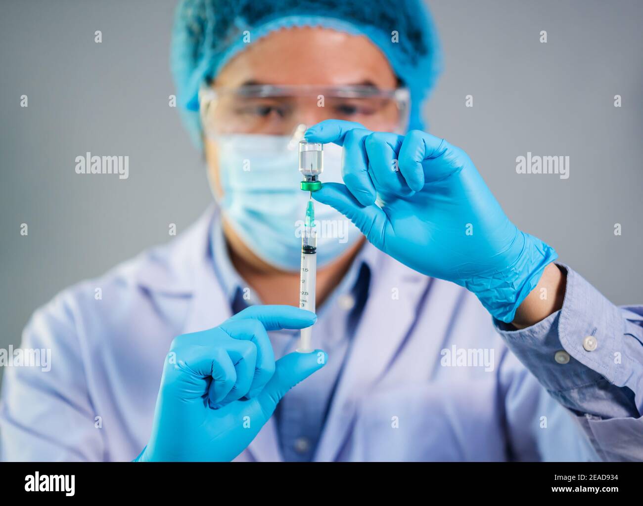 male doctor drawing vaccine bottle into syringe injection medicine ...