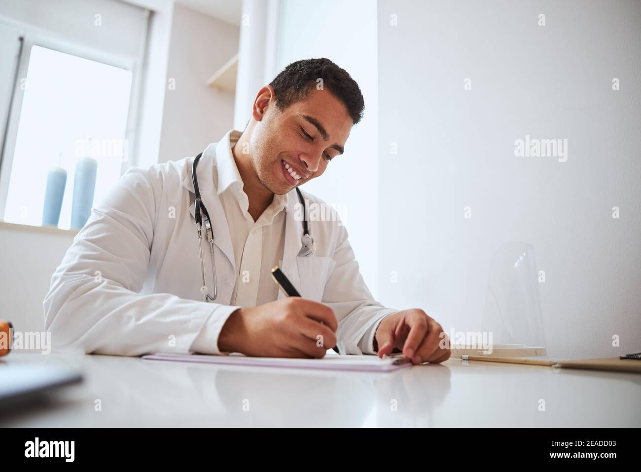 Professional Indian doctor working with documents in medicine office ...