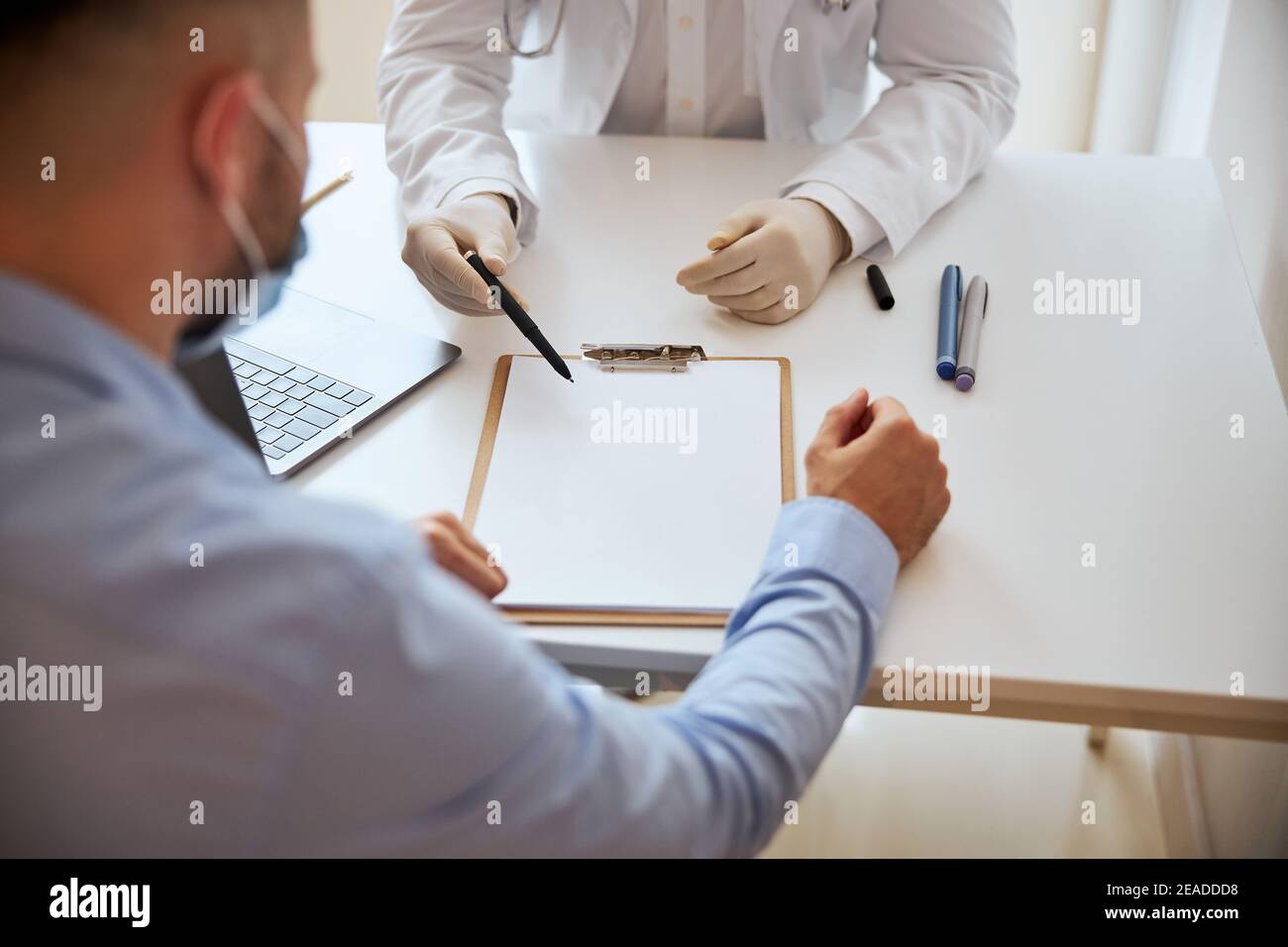 Focused image of doctor showing clean white paper and holding pencil in ...