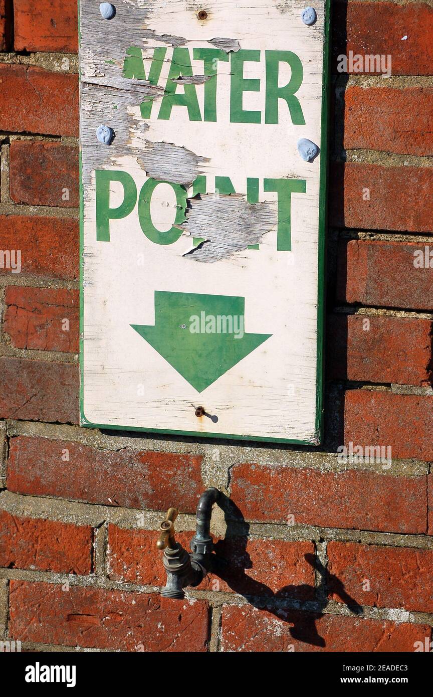 Sign pointing to an exterior tap on a brick wall Stock Photo - Alamy