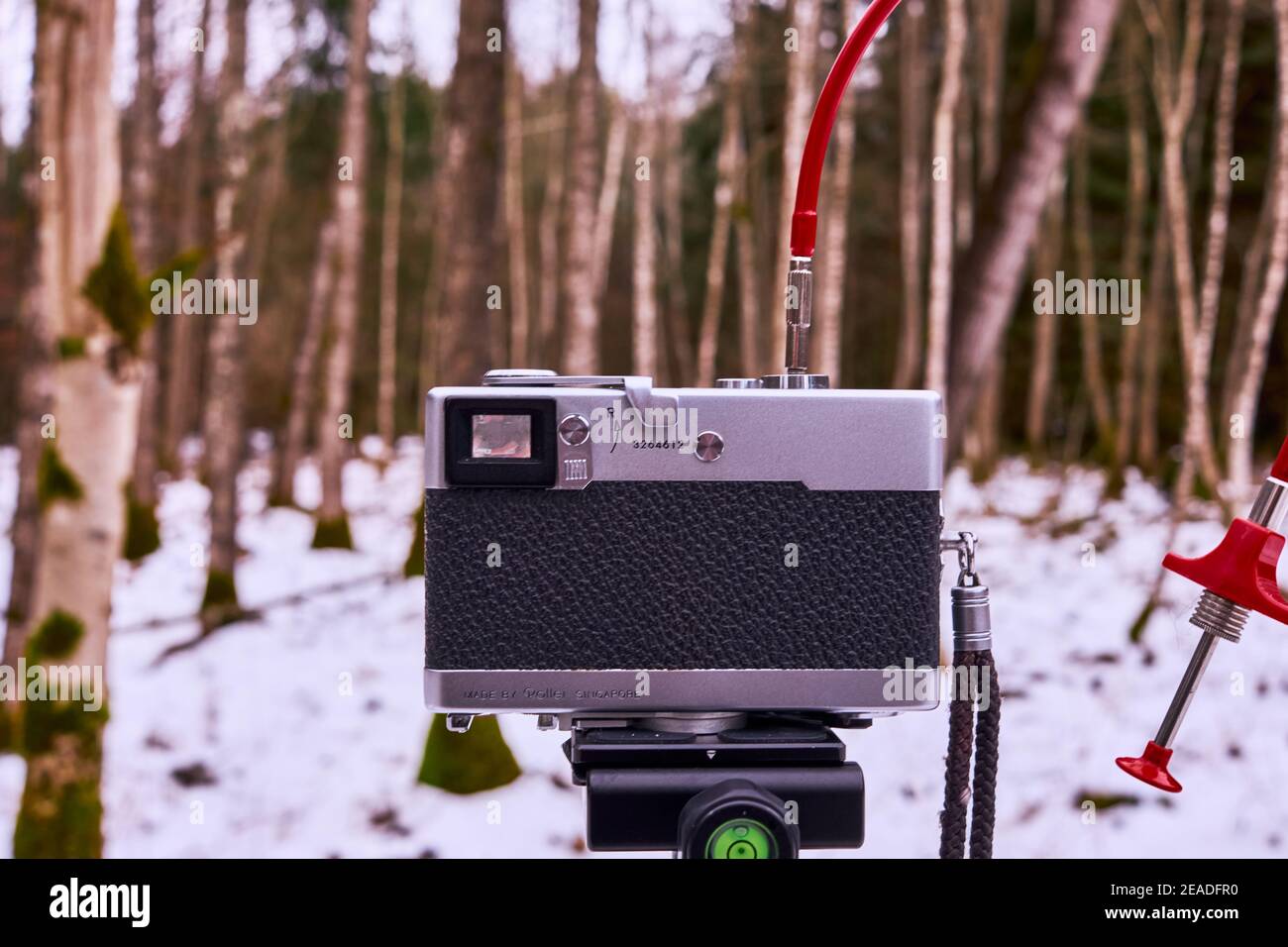 Closeup shot o a photo camera on a tripod in a forest with lots of snow ...