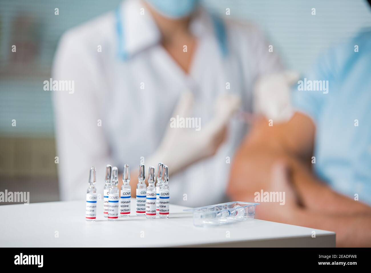 Female doctor with surgical mask and in gloves giving vaccine injection ...