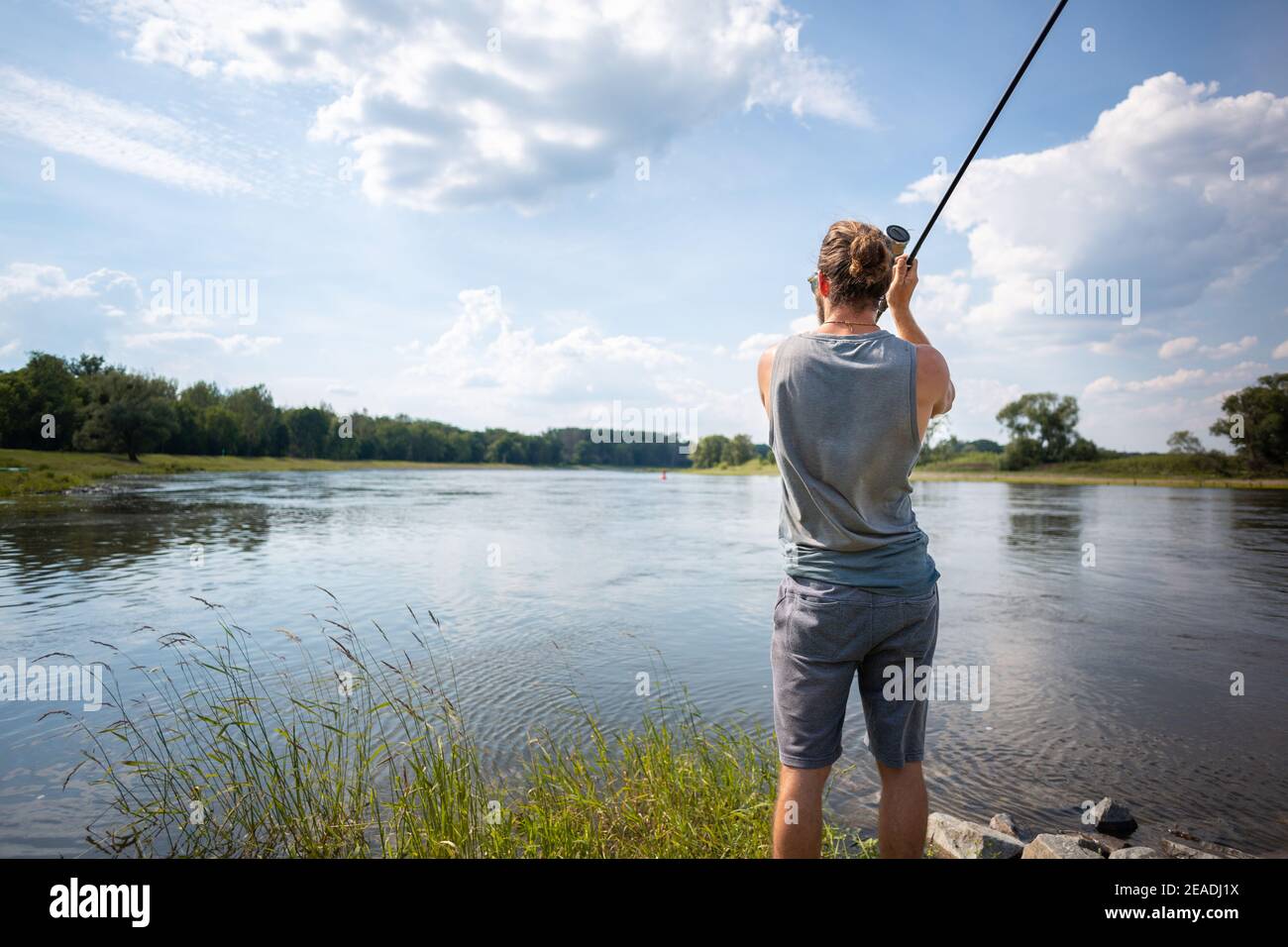 Young fisher on a river bank casting a fishing rod Stock Photo - Alamy
