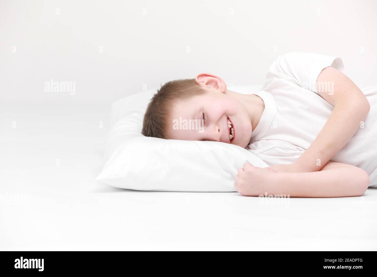 portrait of a happy cute little boy waking up in the morning and lying ...