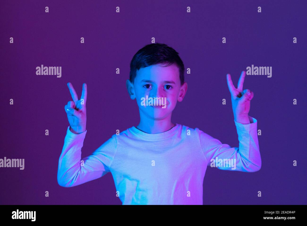 a child making the victory gesture with his hand illuminated with neon ...
