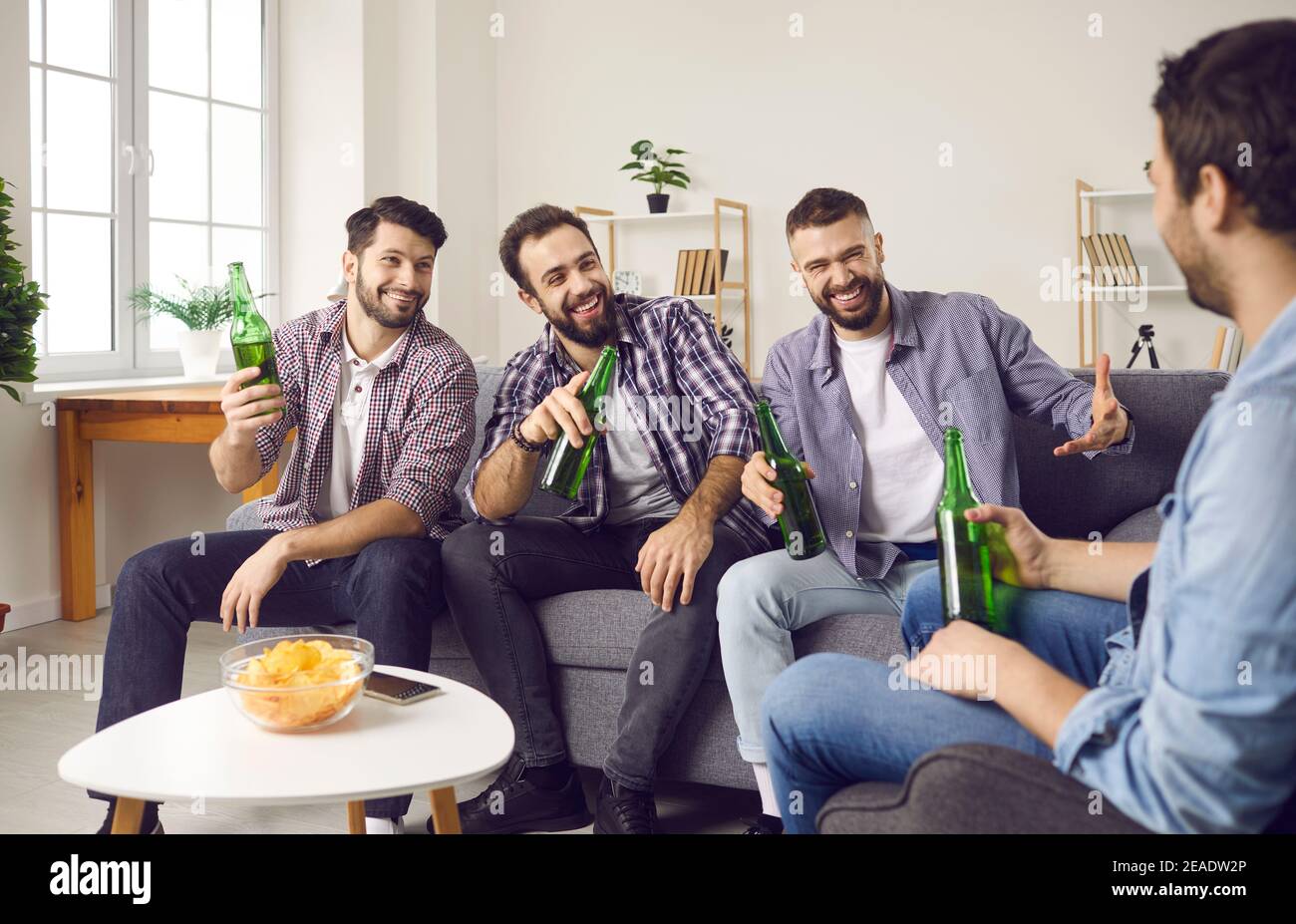 Group of happy friends sitting on sofa, drinking beer, sharing funny ...