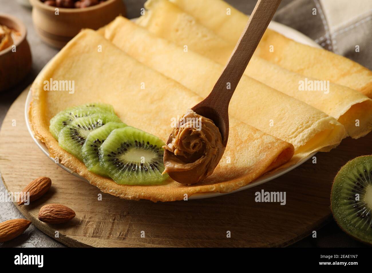 Concept of breakfast with crepes with kiwi and spoon with peanut butter ...