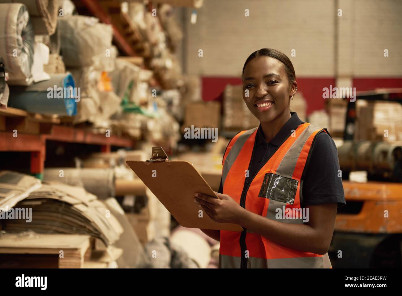Smiling young African female warehouse worker doing inventory Stock ...
