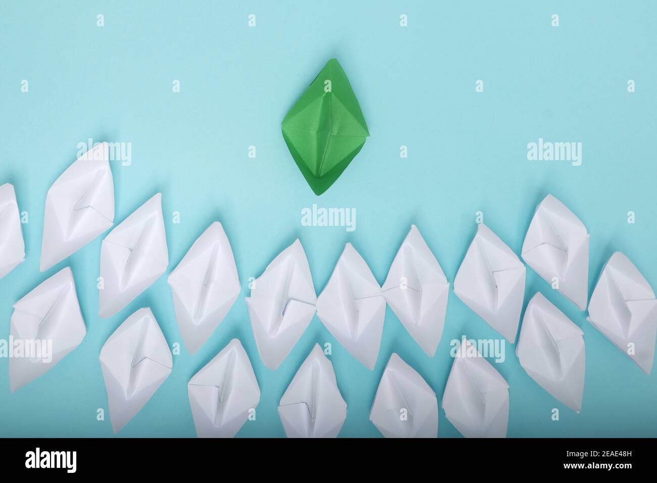 Leadership concept with Green paper ship leading among group of white ...