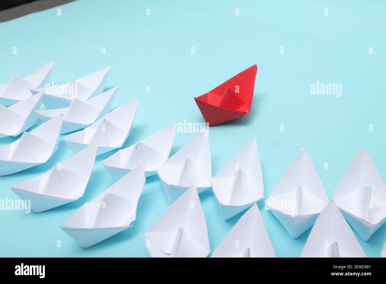 Leadership concept with red paper ship leading among group of white ...