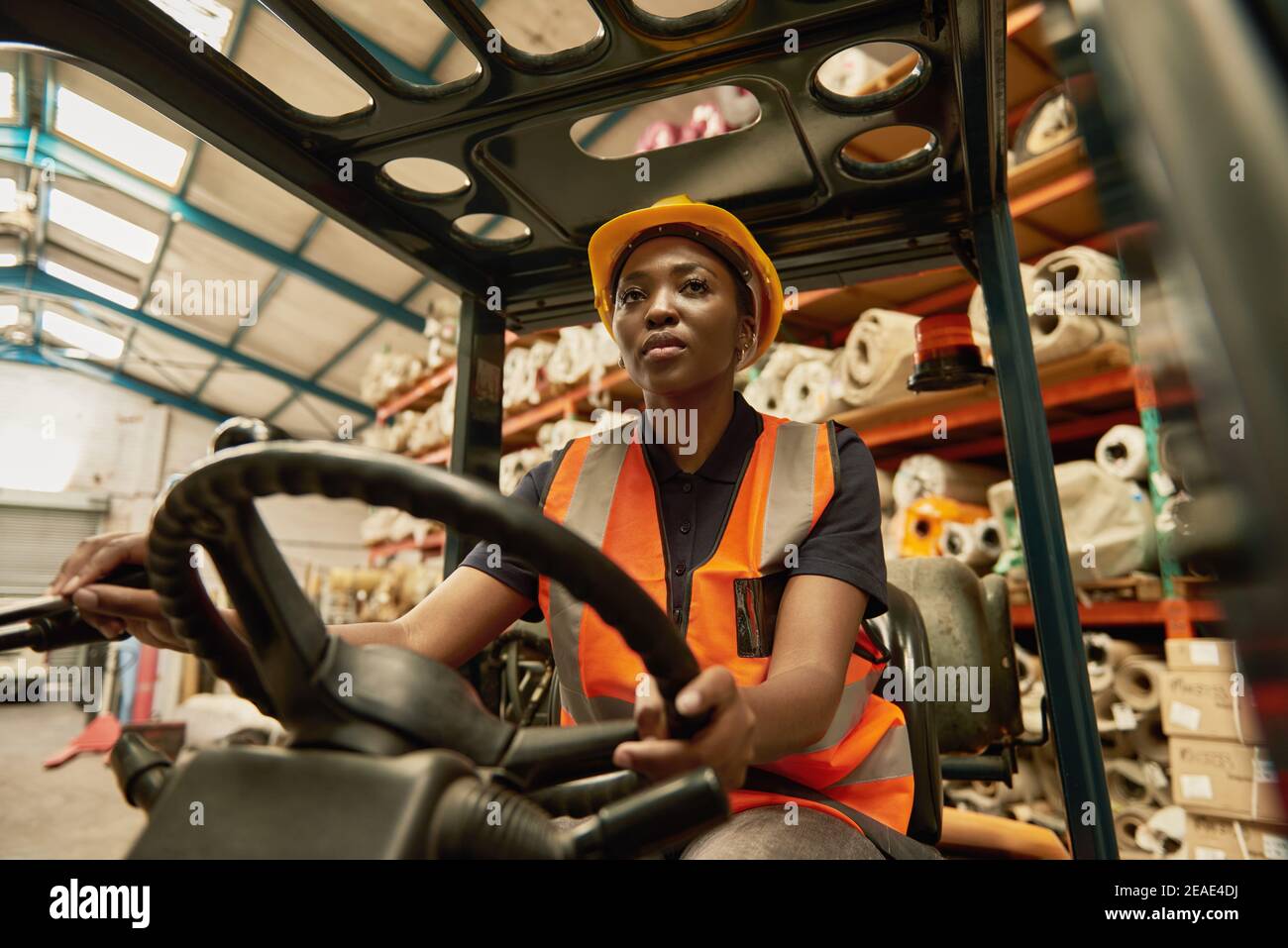 Young African female forklift operator driving around a warehouse Stock ...