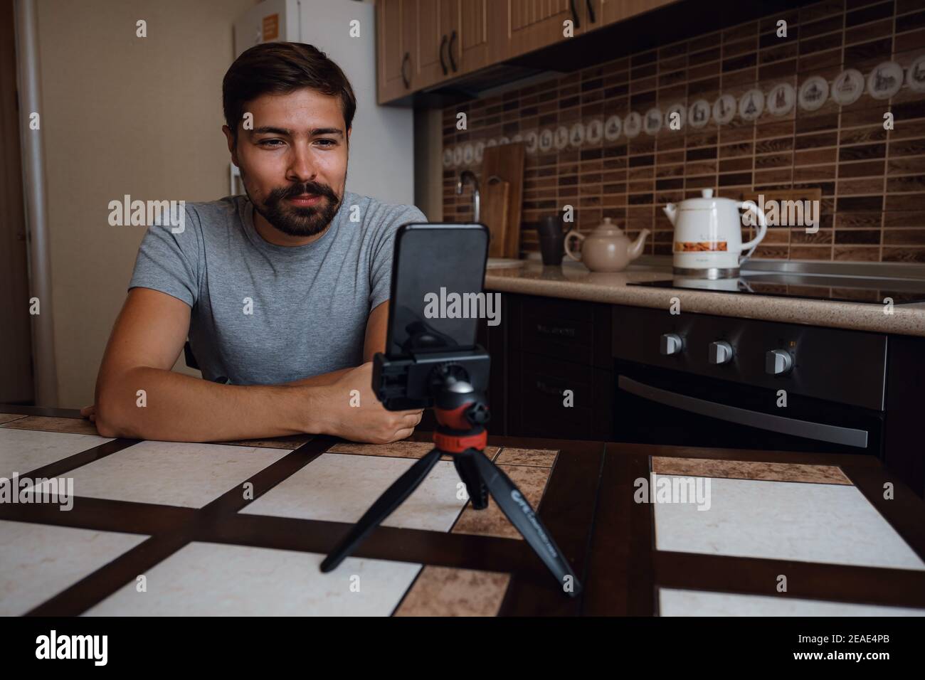 Young man having video call via smartphone in the home office. Virtual ...