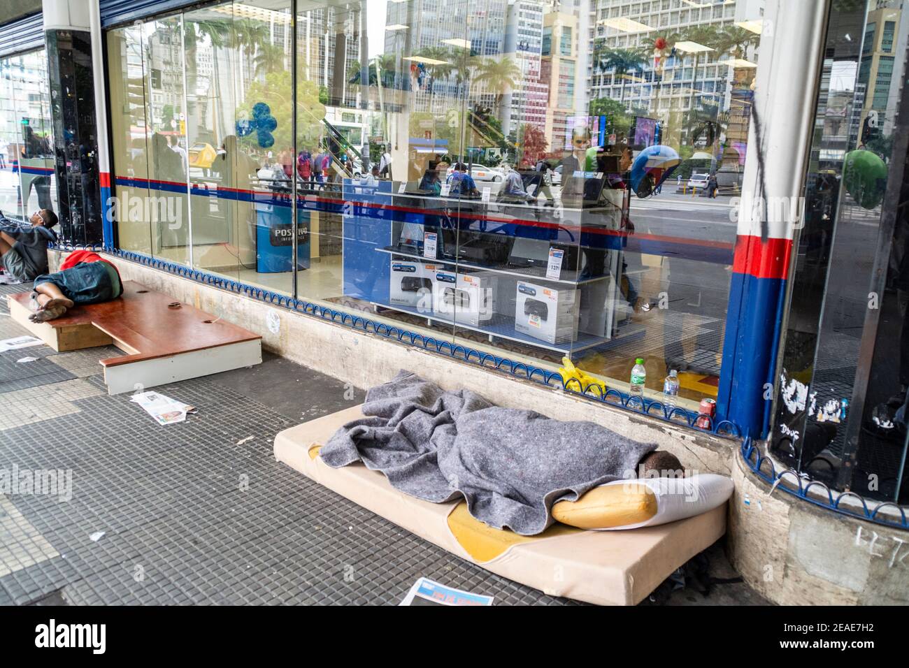 Homeless people sleeping rough in front of a large department store is ...