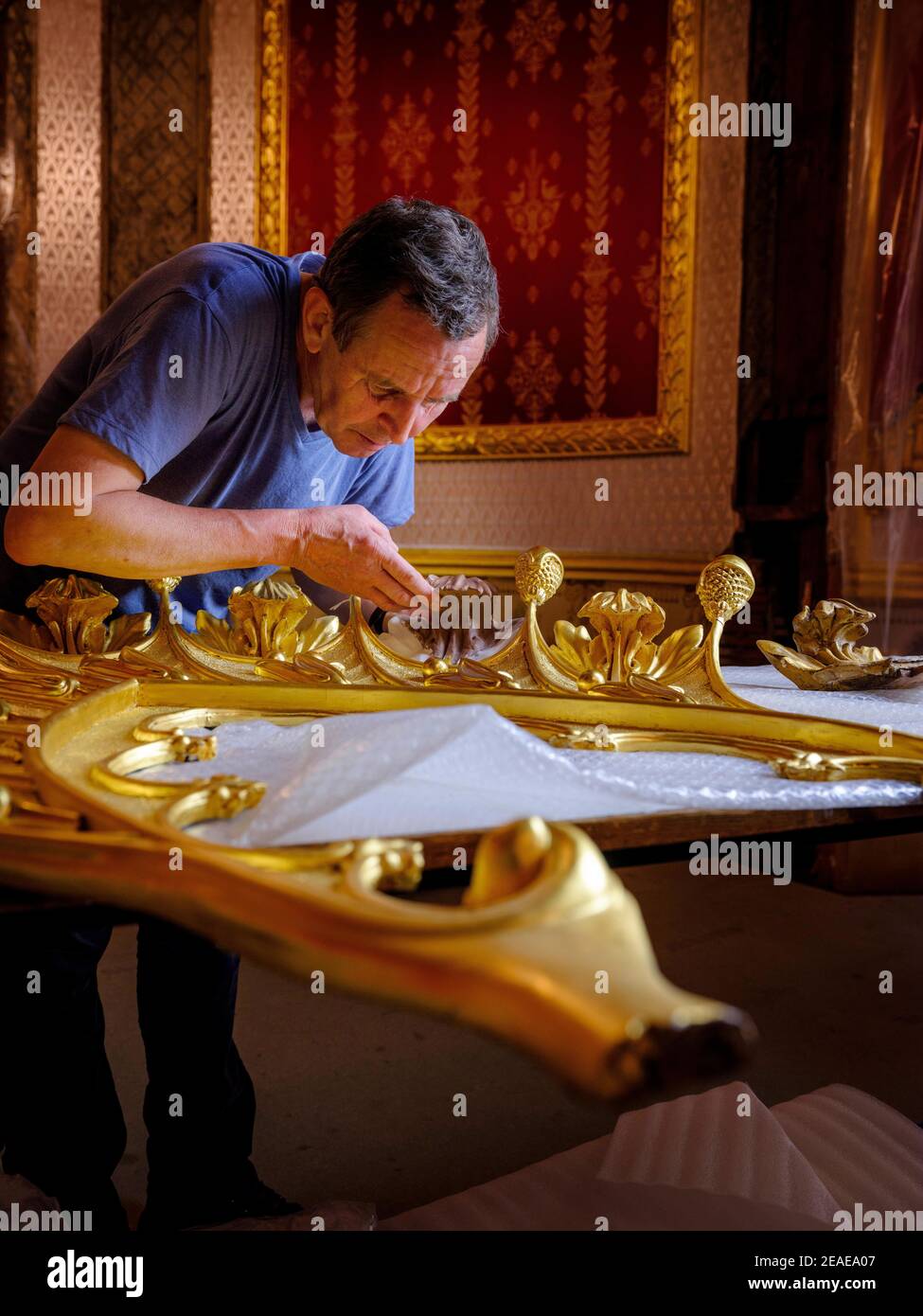 A conservator at work gilding a moulding during the restoration of the ...
