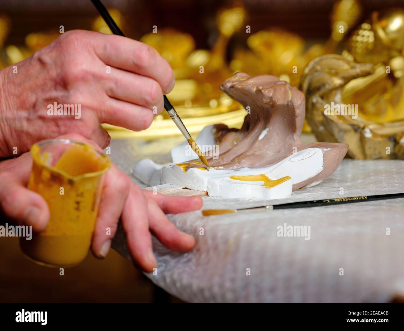 A conservator at work gilding a moulding during the restoration of the ...