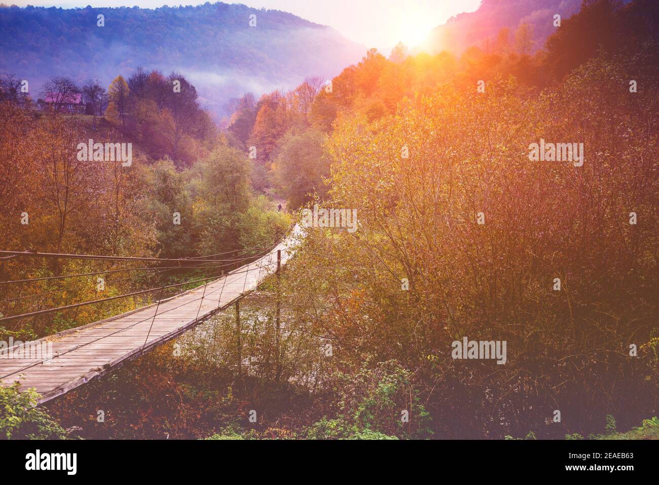 Wooden suspension rope bridge over mountain river on a foggy morning ...