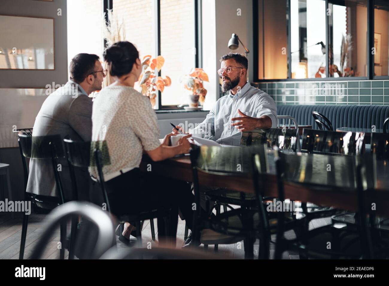 Manager talking during a casual meeting with his staff over coffee ...
