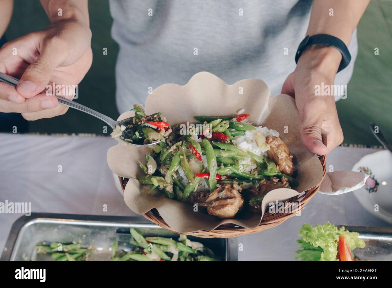 Person hand puts white vegetables from the steel pan to wooden paper ...