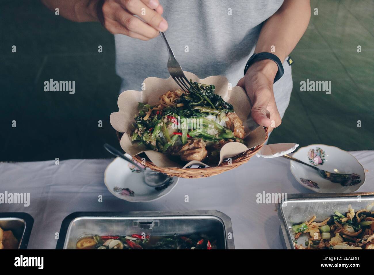 Person hand puts white vegetables from the steel pan to wooden paper ...