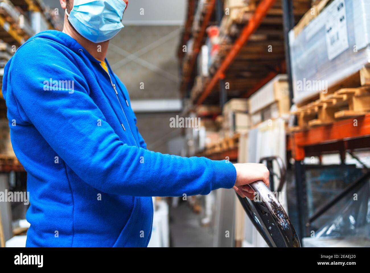 Warehouse worker in a protective mask with a hand pallet truck Stock ...