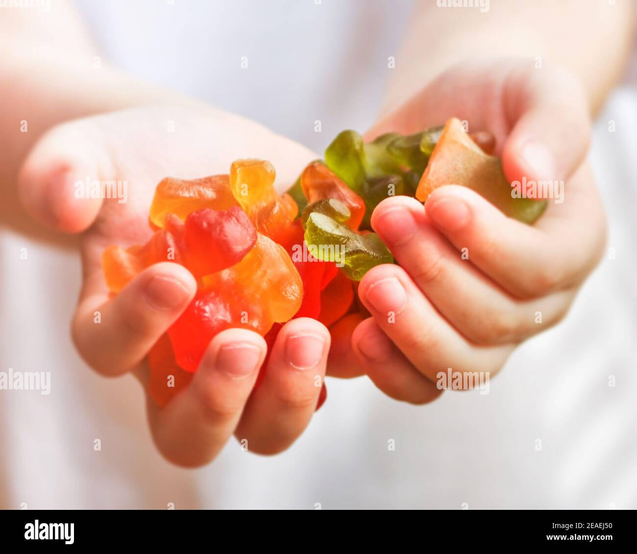 Hands of a boy sharing gummies or candies. Kid's hands full of gummies ...