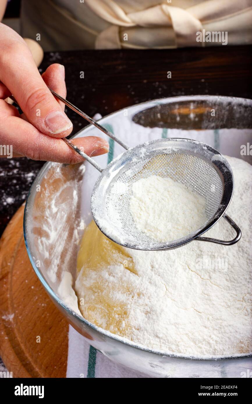 Sifting flour through a sieve. Dough preparation process. Workflow in a ...