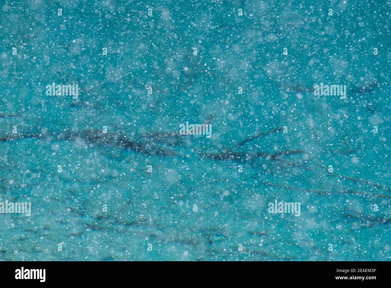 snowfall over turquoise water of an alpine lake in Valais Stock Photo ...
