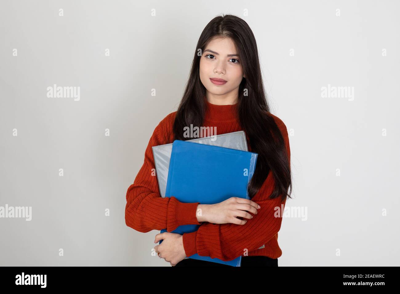 Portrait of a beautiful young lady holding business folders standing ...