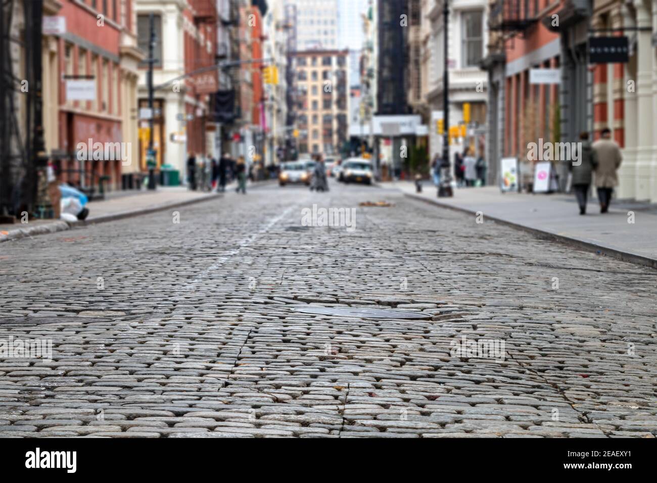 Cobblestone street with busy intersection blurred in the background in ...