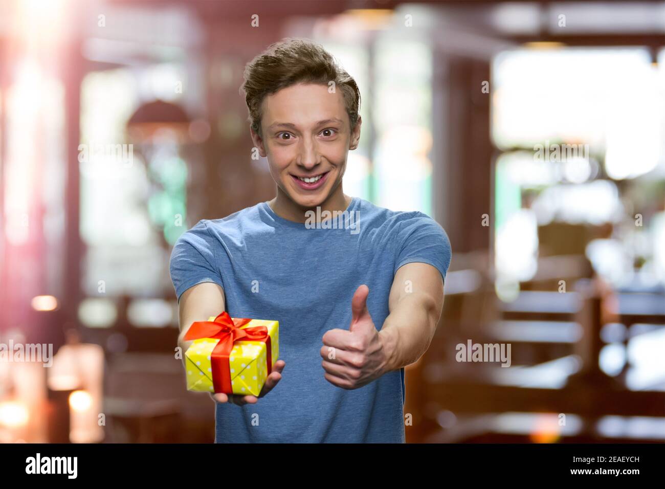 Positive boy is showing thumb up gesture and gift box Stock Photo - Alamy