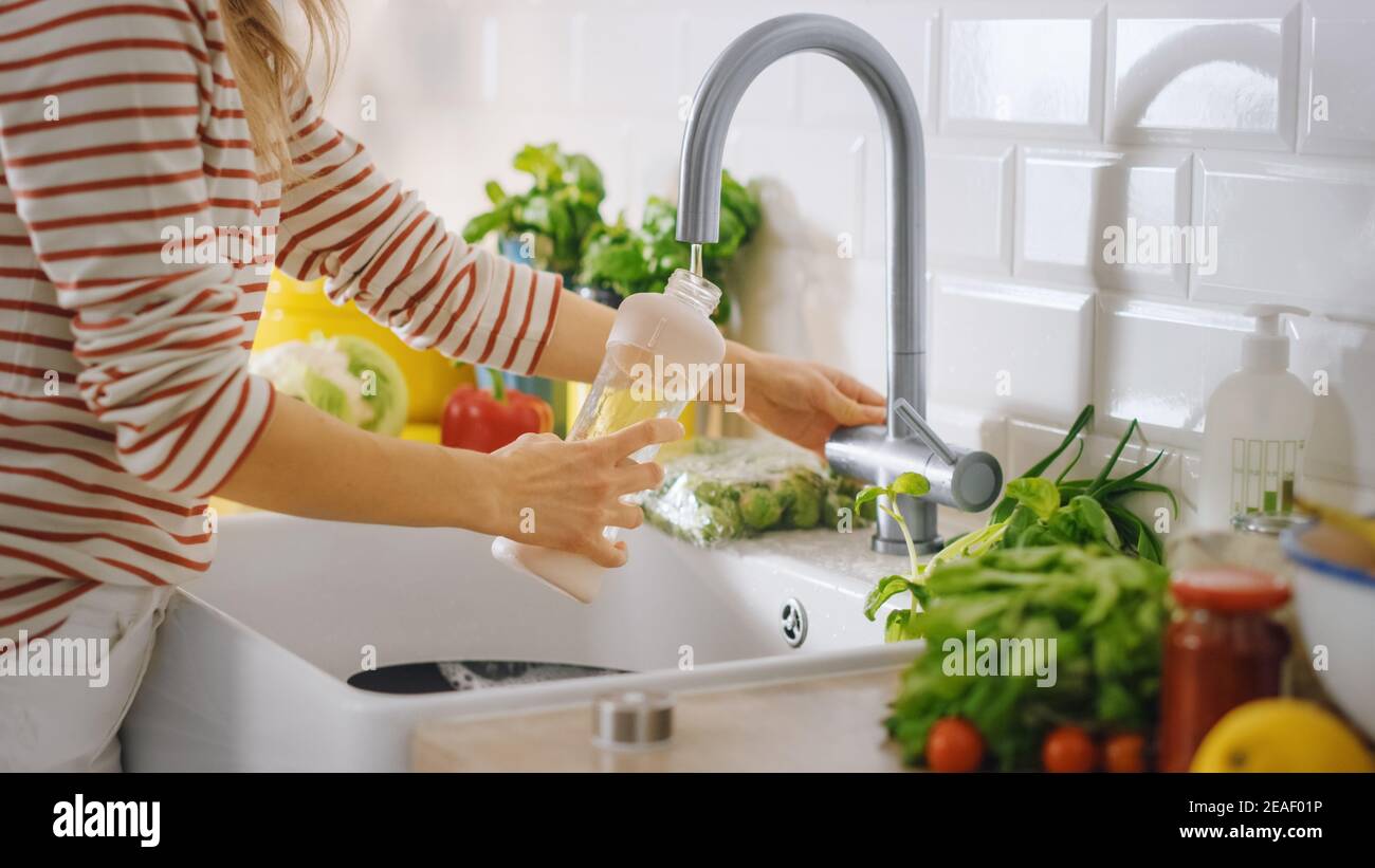 Close Up Shot of a Woman Filling a Reusable Plastic Bottle with Clean ...