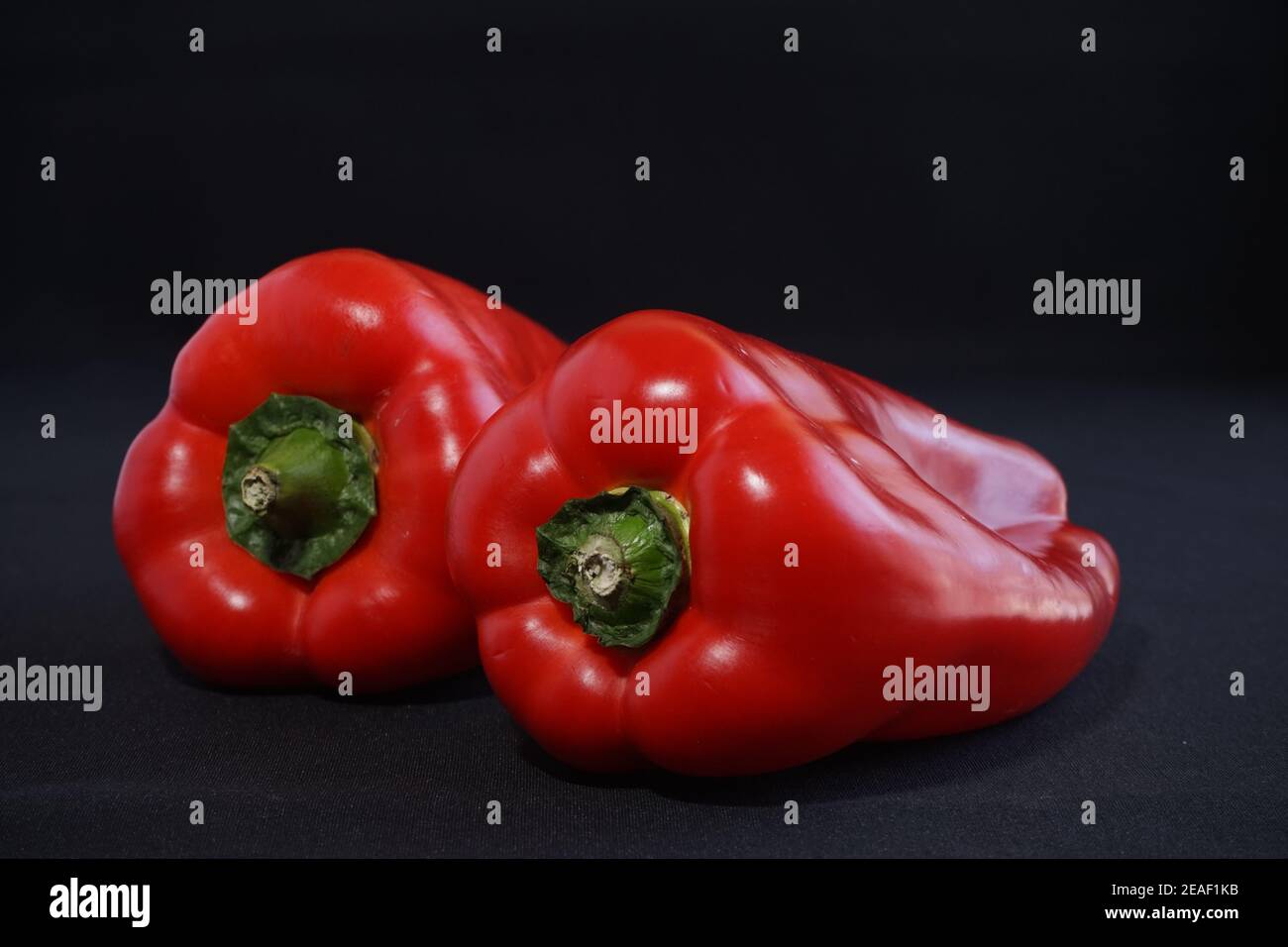 two red peppers on black background Stock Photo - Alamy