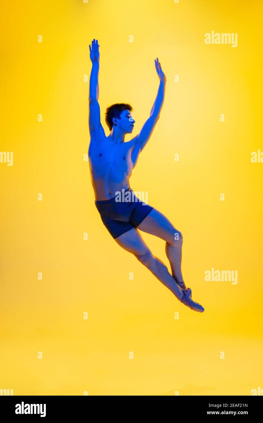 Flying, jumping. Young and graceful ballet dancer on yellow studio ...