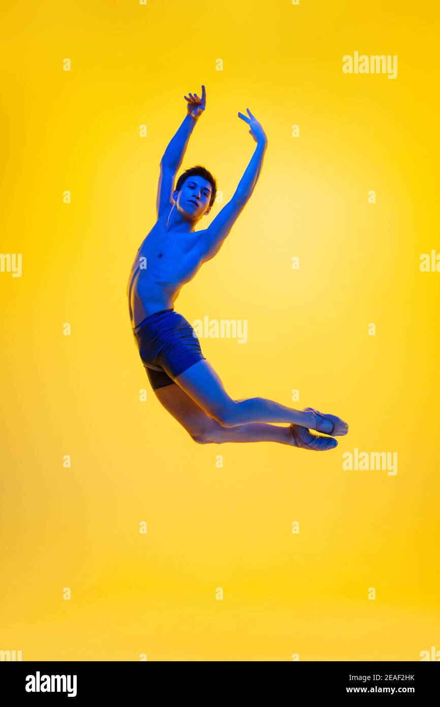 Flying, jumping. Young and graceful ballet dancer on yellow studio ...