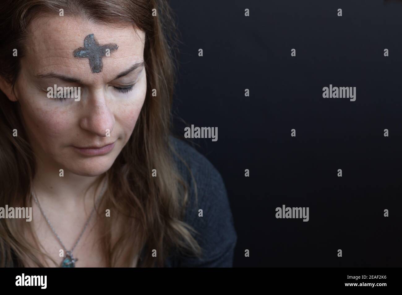 woman with ashes cross on forehead for ash wednesday looking down, with ...