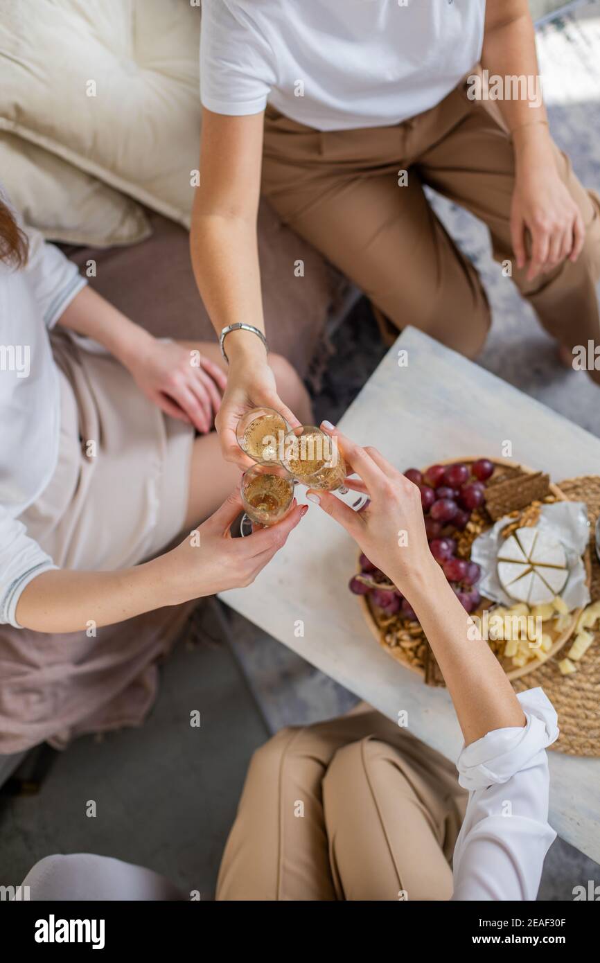 Three happy female friends drinking champagne cheers together laughing ...