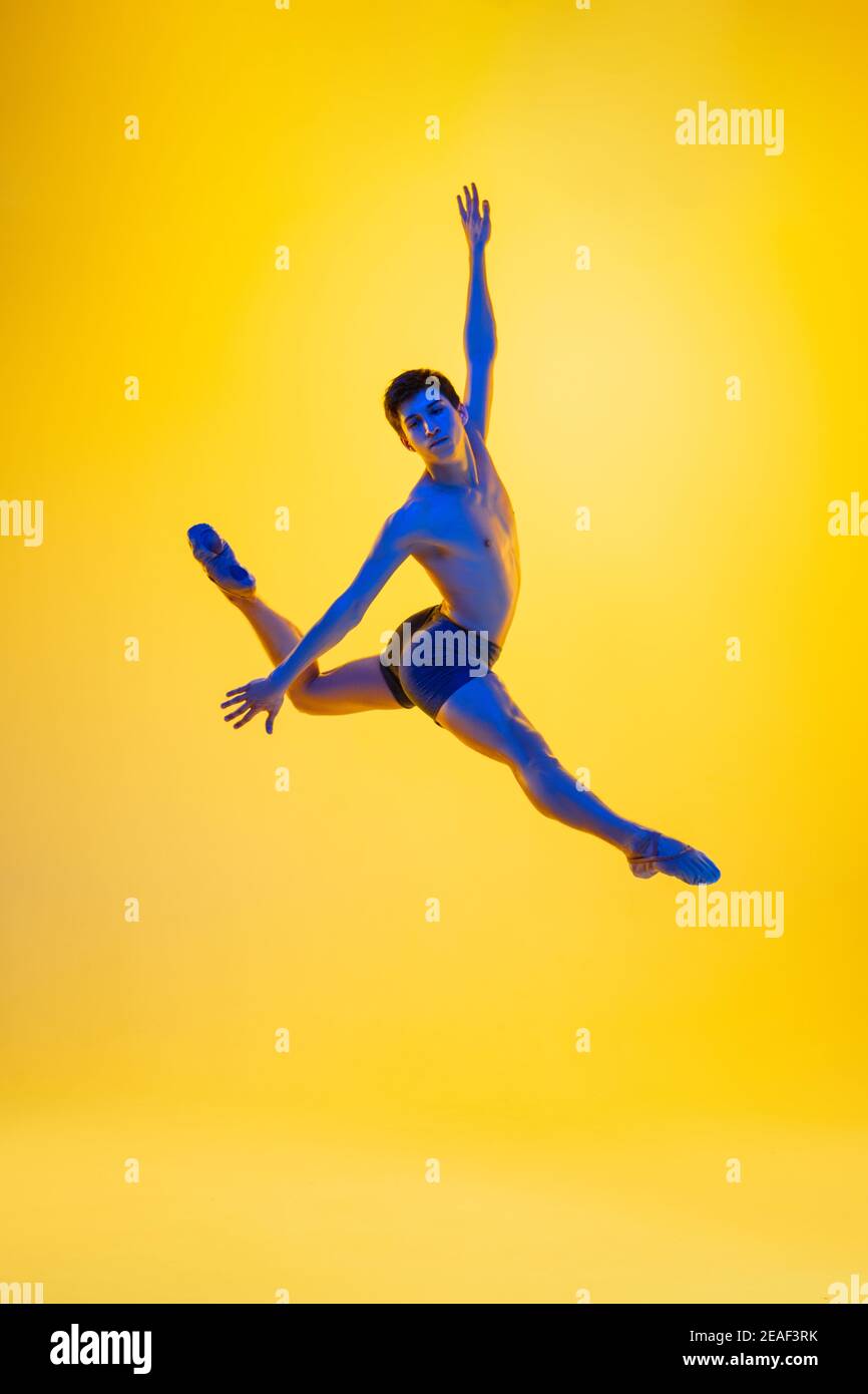 Powerful. Young and graceful ballet dancer on yellow studio background ...