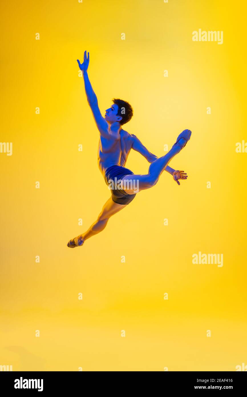 Powerful. Young and graceful ballet dancer on yellow studio background ...