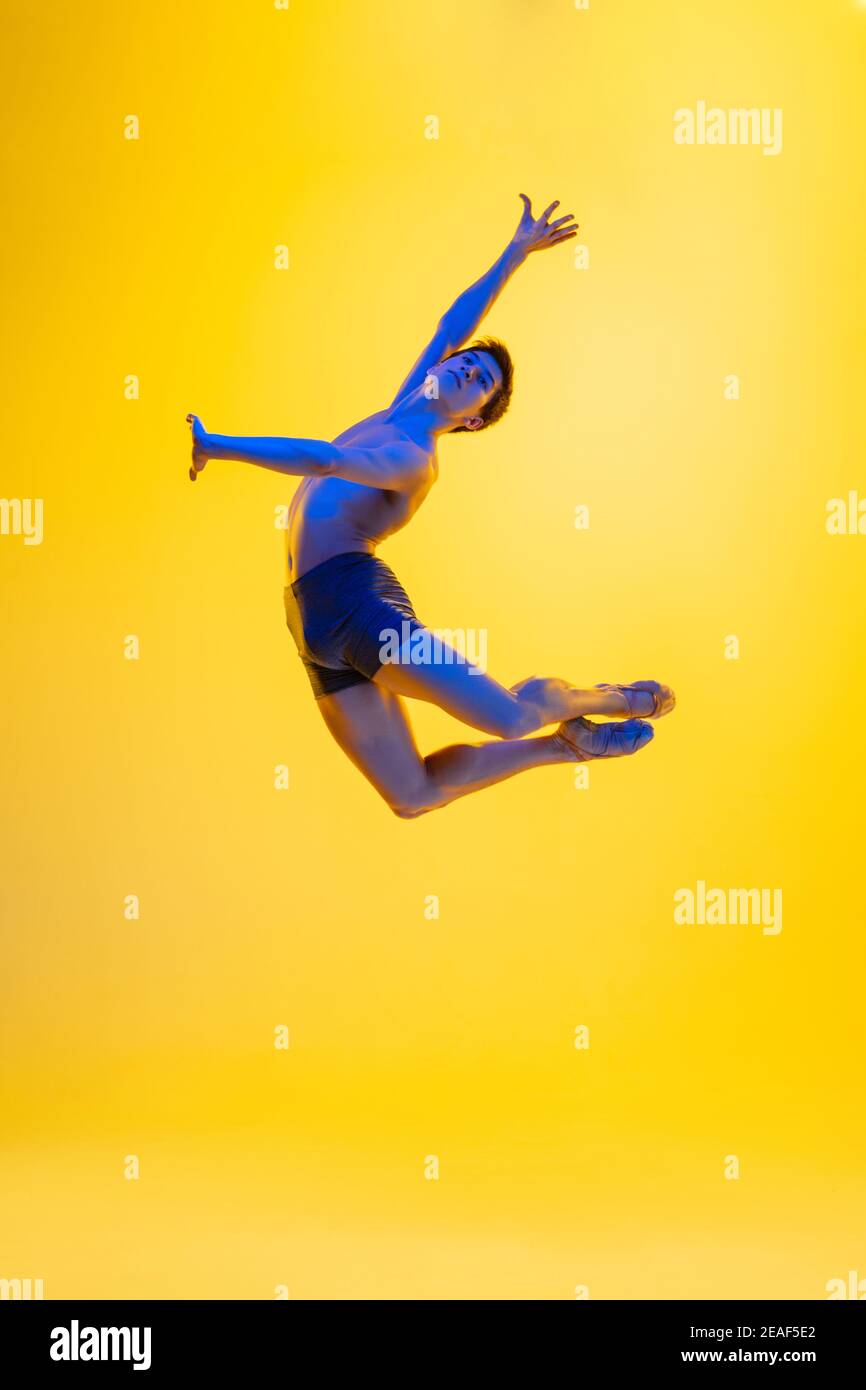 Artwork. Young and graceful ballet dancer on yellow studio background ...