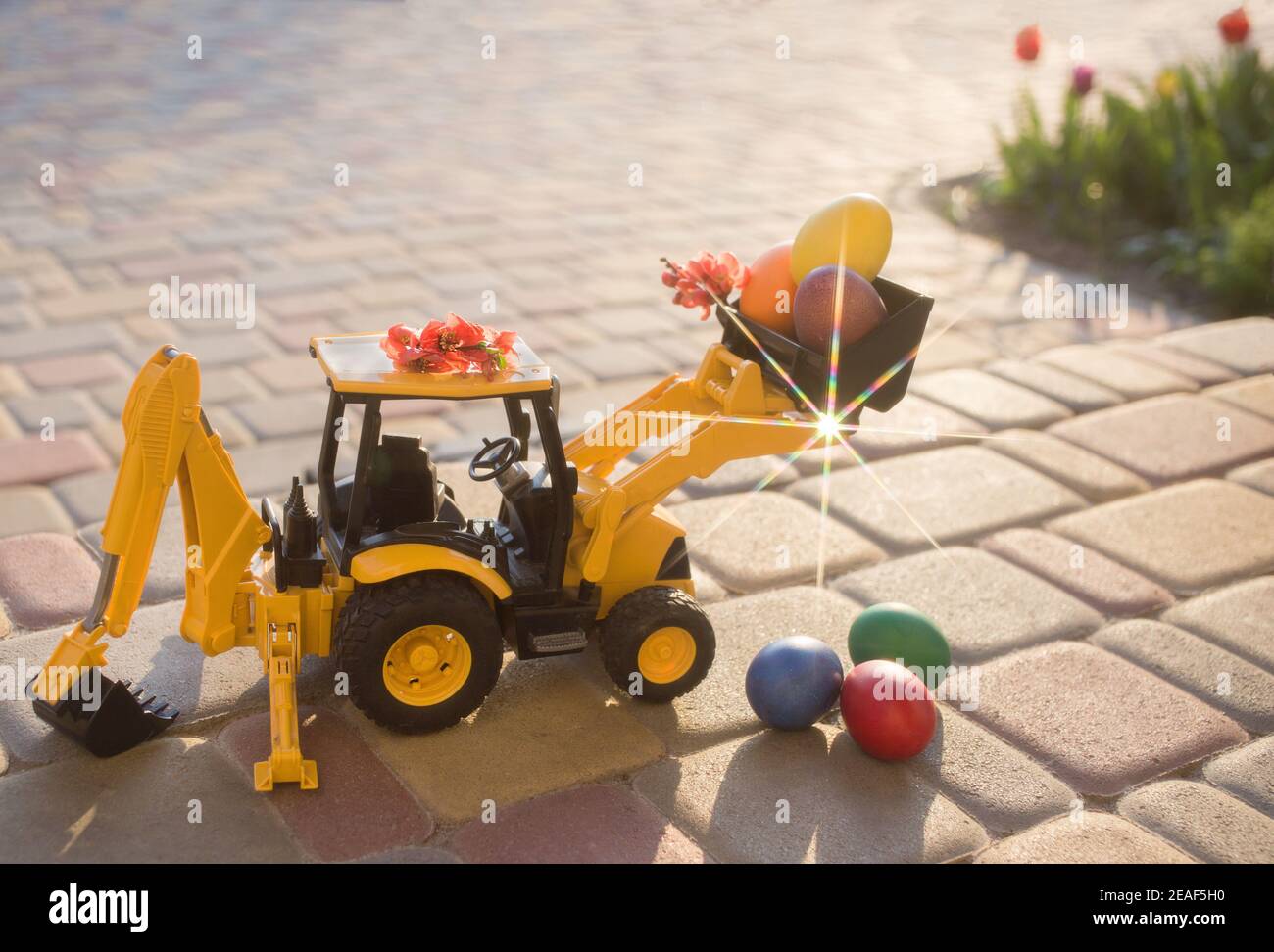 toy excavator - a loader stands on the paving slabs, next to it ...