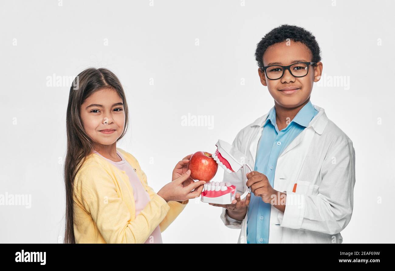 health of child's teeth. Cute boy and girl bites an apple using human ...