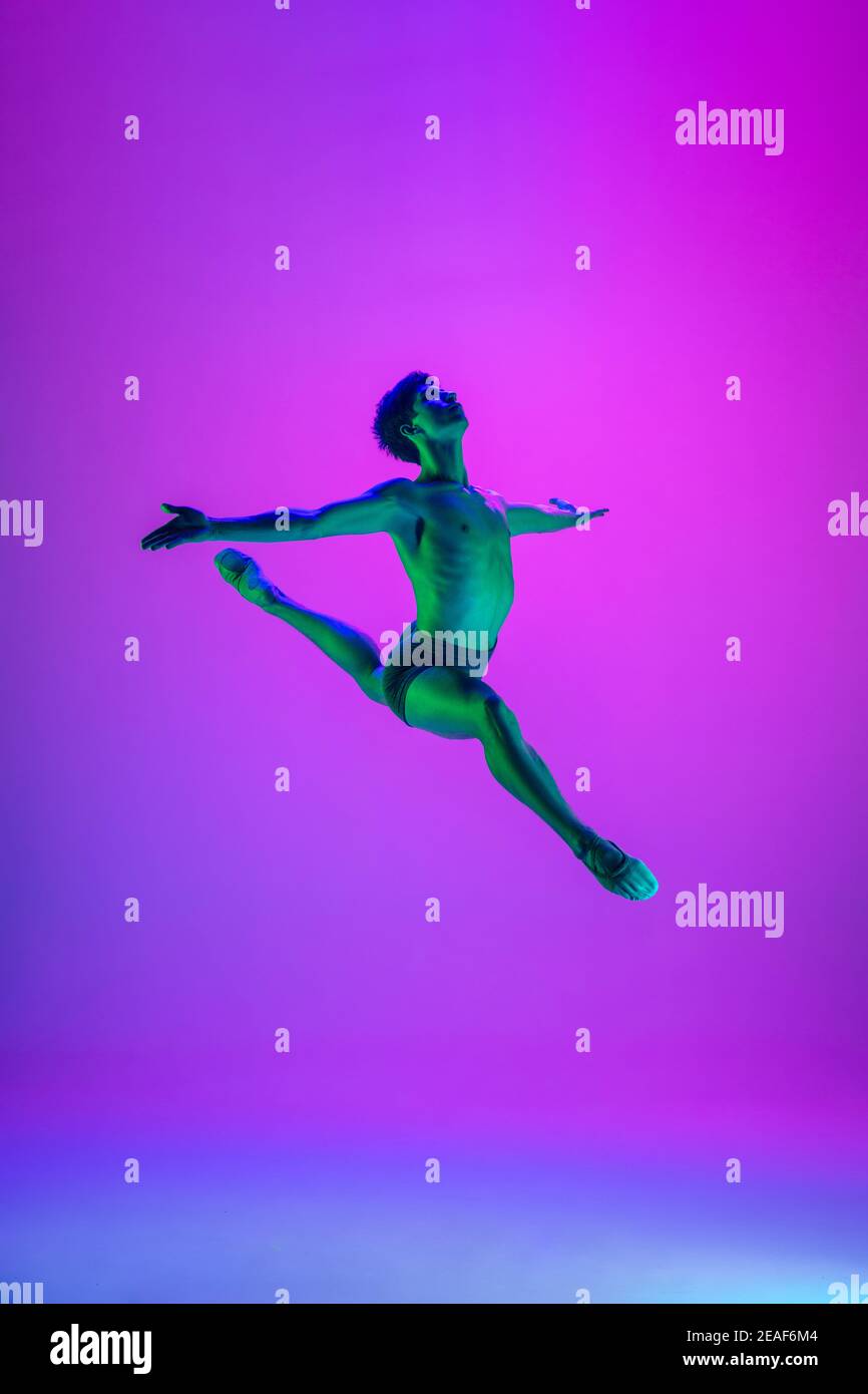 Weightless. Young and graceful ballet dancer on purple studio ...