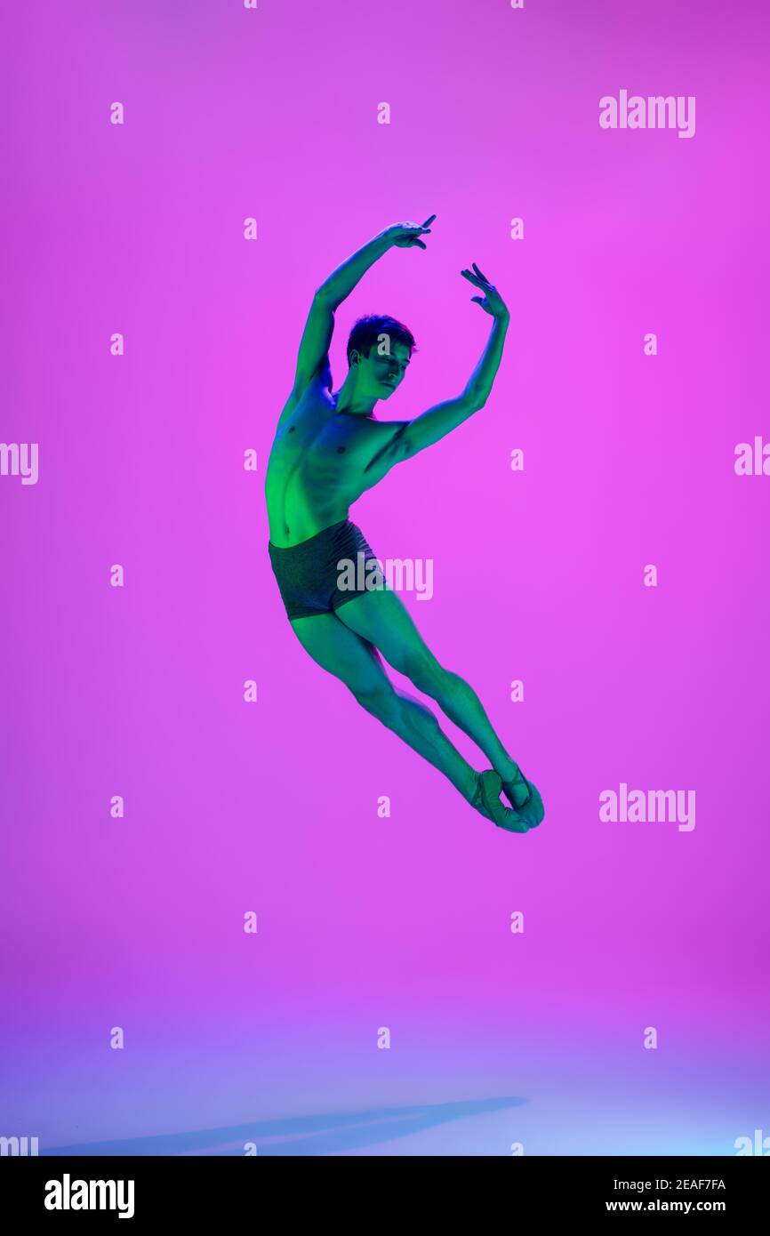 Power. Young and graceful ballet dancer on purple studio background in ...
