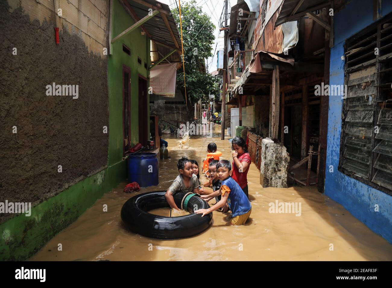 Children play in floodwaters using rubber tires during the aftermath of ...